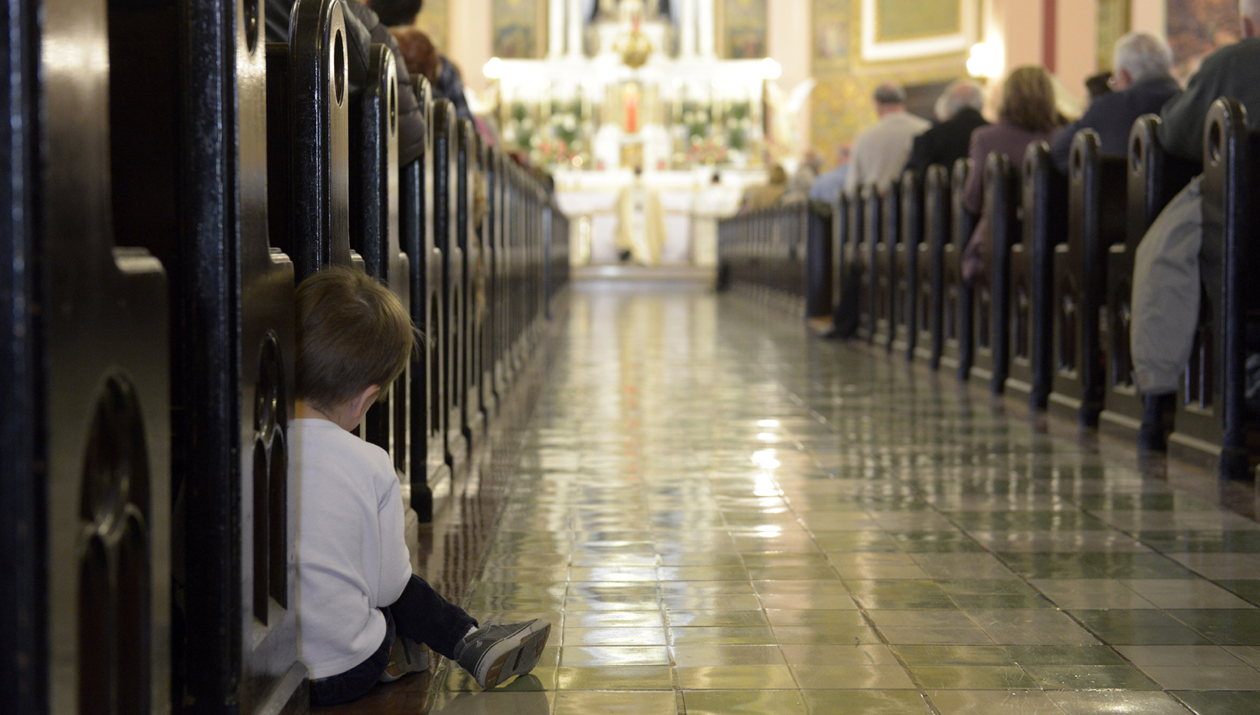 Boy in pew aisle at Mass small | Vianney Vocations